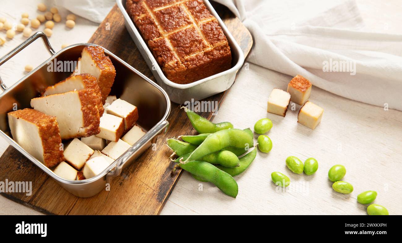 Soy food. Baked tofu cheese on a board, soybeans. Vegan product. Banner ...