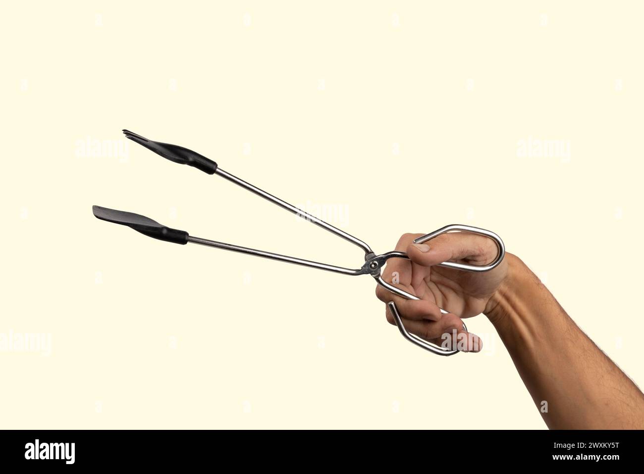 Male hand holding kitchen tong isolated beige background Stock Photo ...