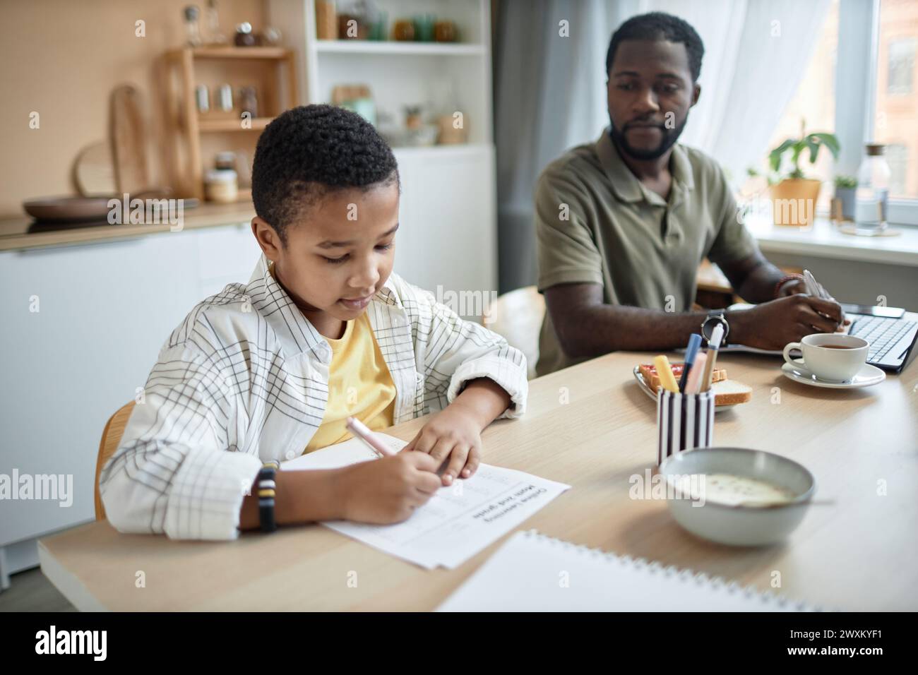 Portrait of young African American boy doing homework at kitchen table ...