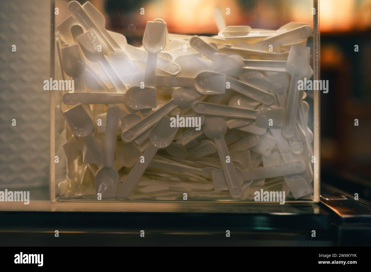 A multitude of white plastic spoons neatly arranged in a transparent ...