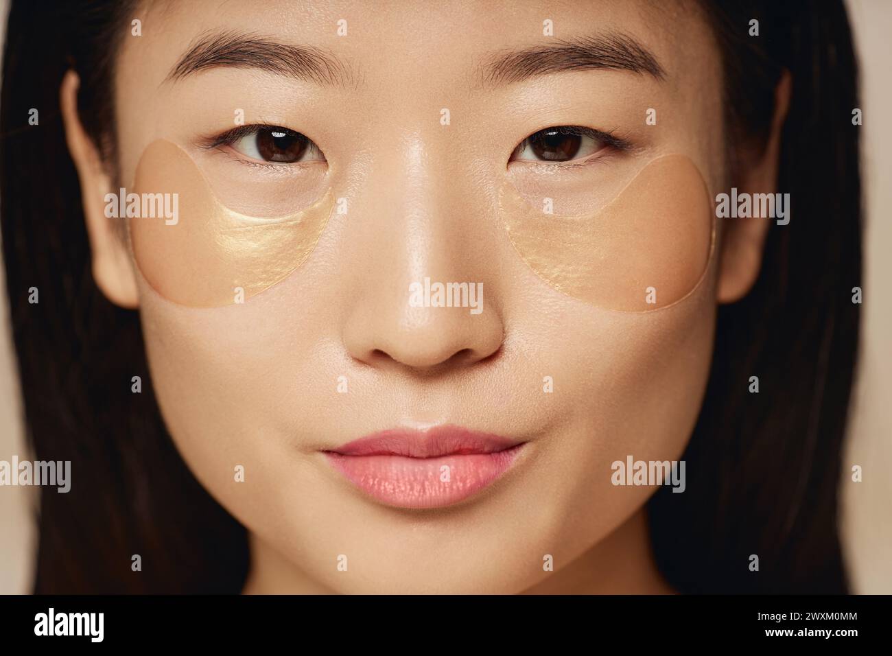 Extreme closeup of young Asian woman with collagen patches under eyes ...