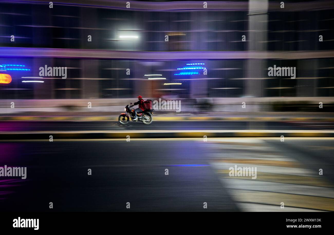 Motorcycle driving on rainy city street at night Stock Photo - Alamy