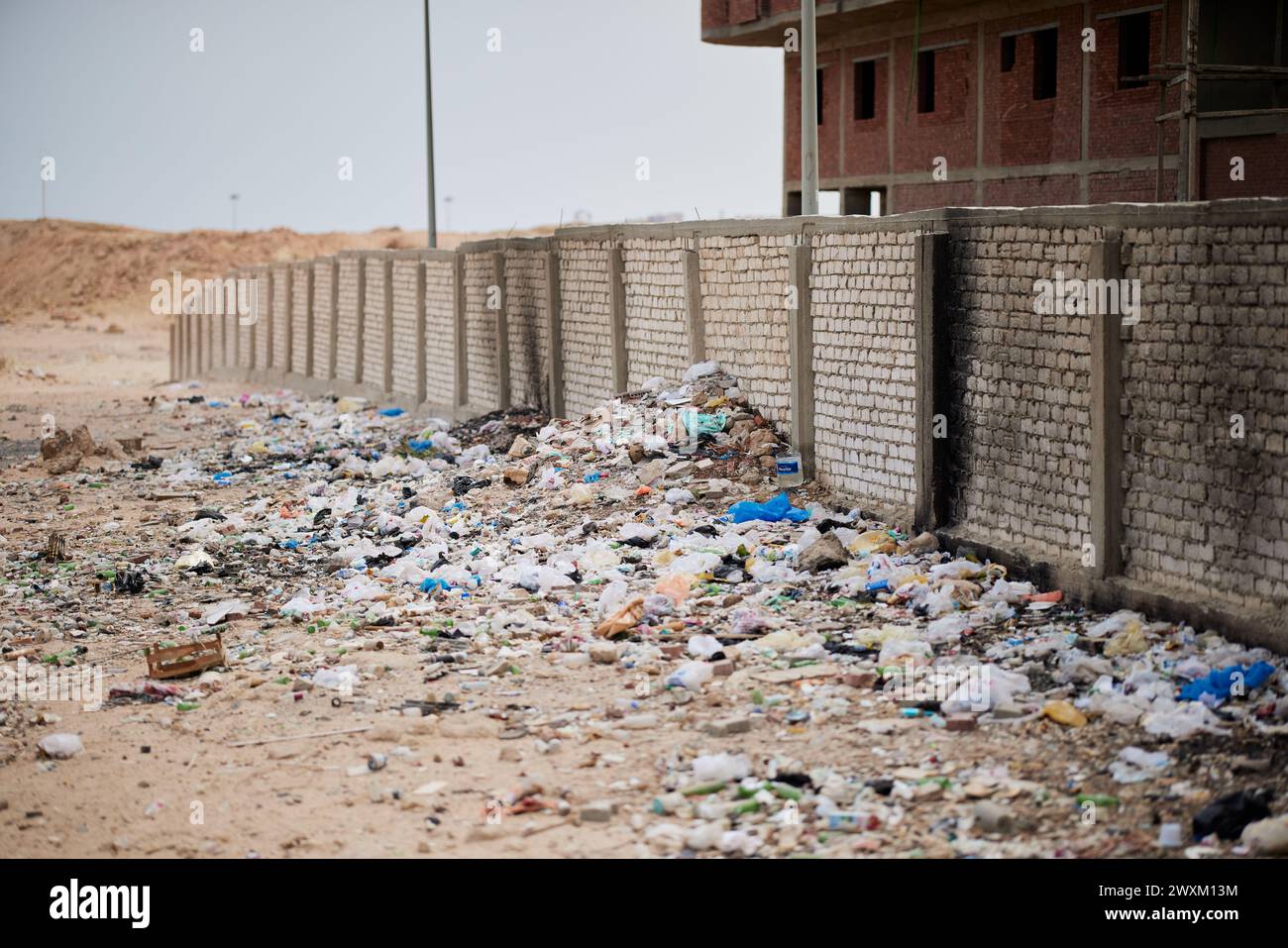 Dirty rubble and garbage in front of a building with a concrete fence ...