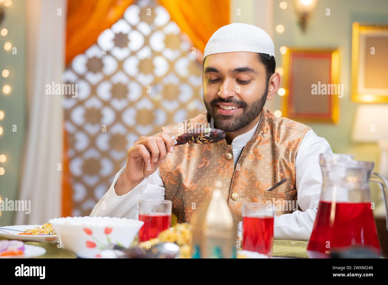 Indian Muslim young man enjoys eating chicken leg piece during during ...