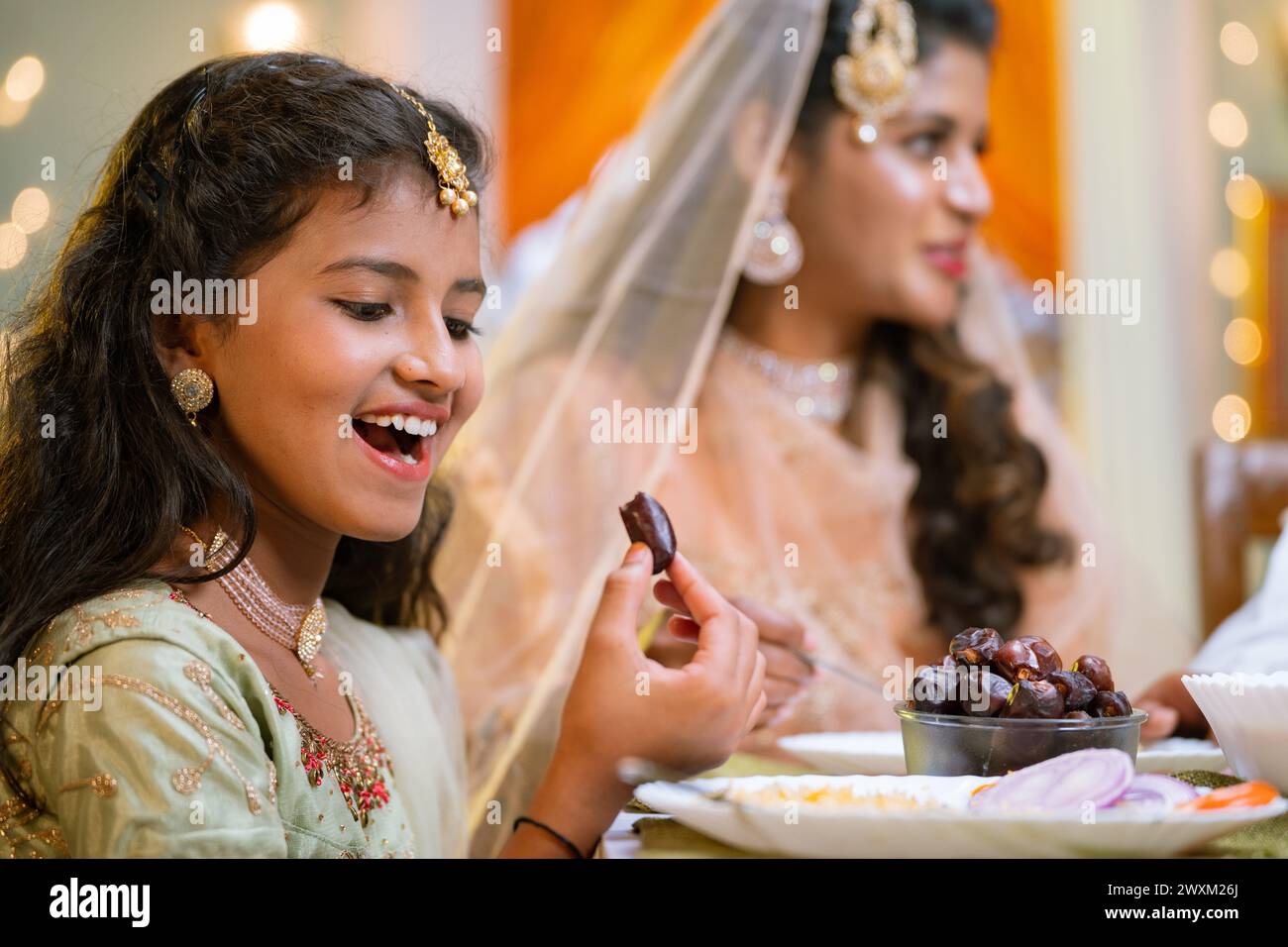 Happy excited indian girl eating dates while having dinner during ...