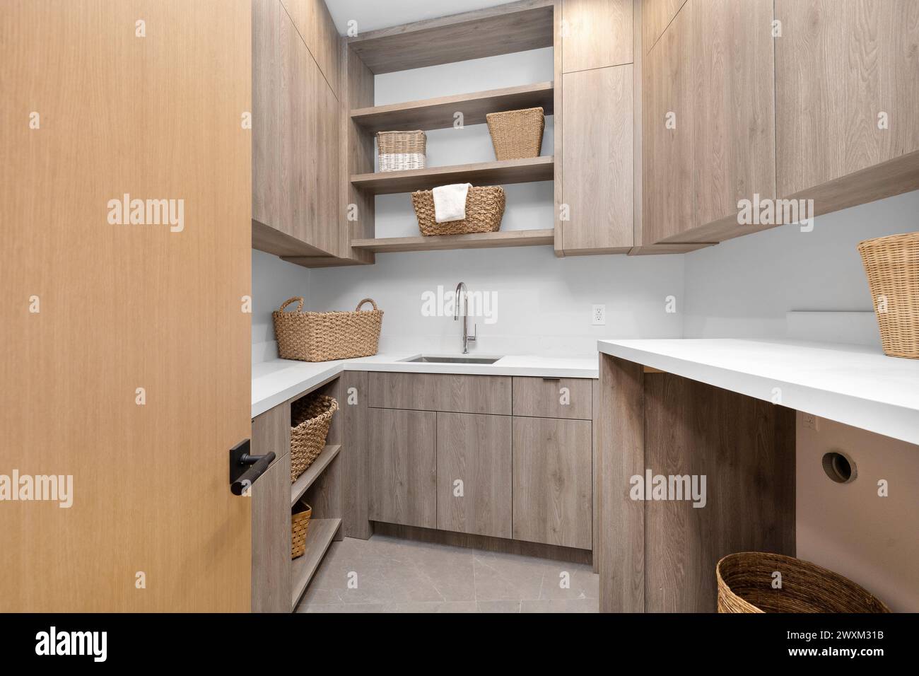 A small laundry room with beige furniture and white floor Stock Photo ...