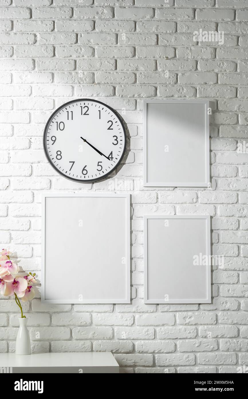 Minimalist White Wall Decor Featuring a Clock and Blank Photo Frames ...