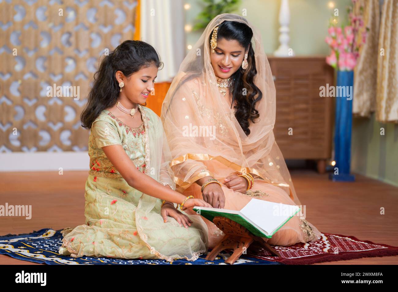 indian muslim woman helping kid to read quran before festing food ...