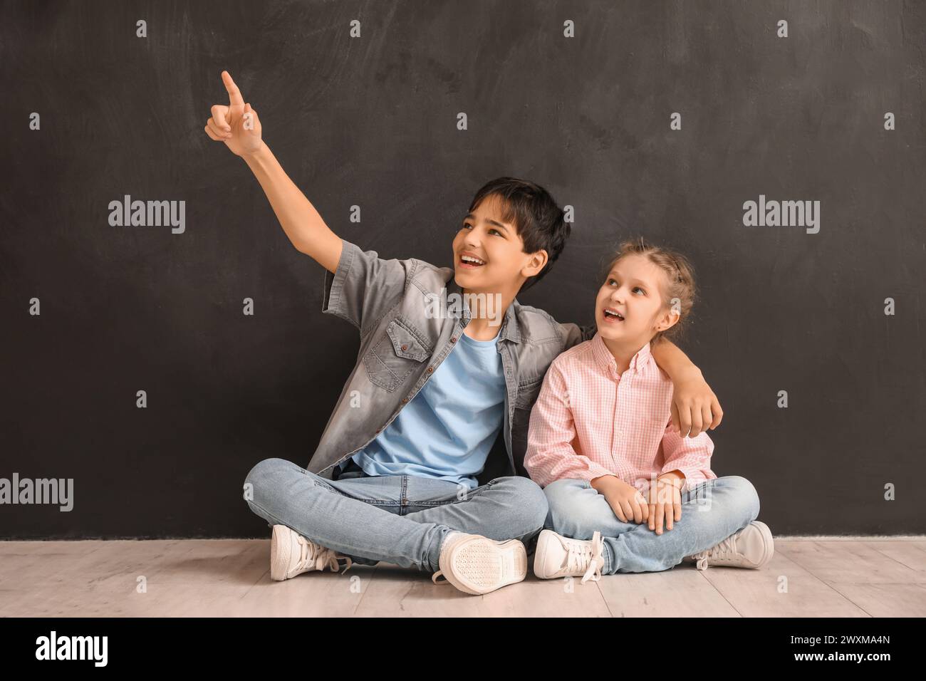 Little children pointing at something near blackboard Stock Photo - Alamy