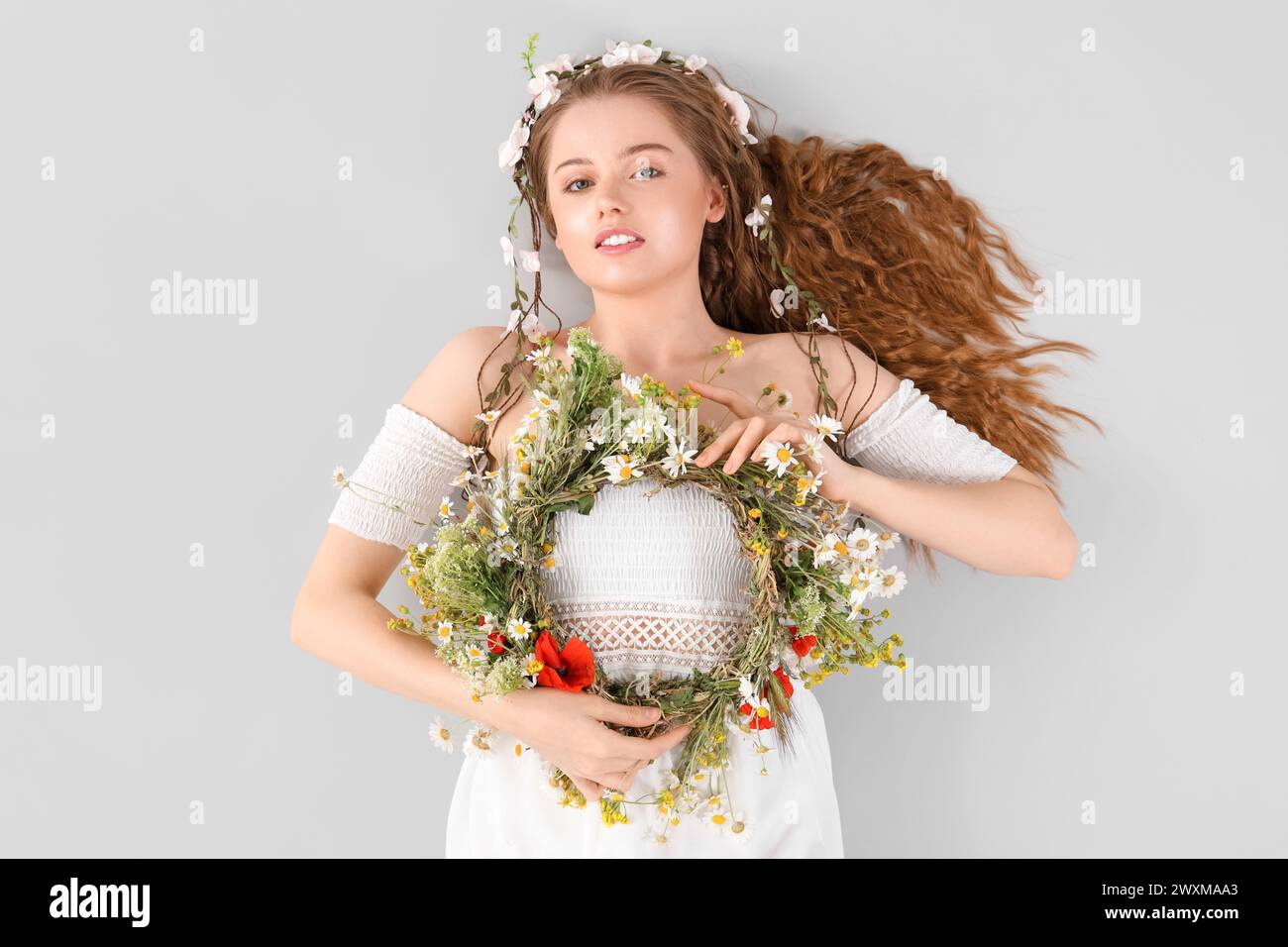 Beautiful young woman with flower wreath on light background. Summer ...