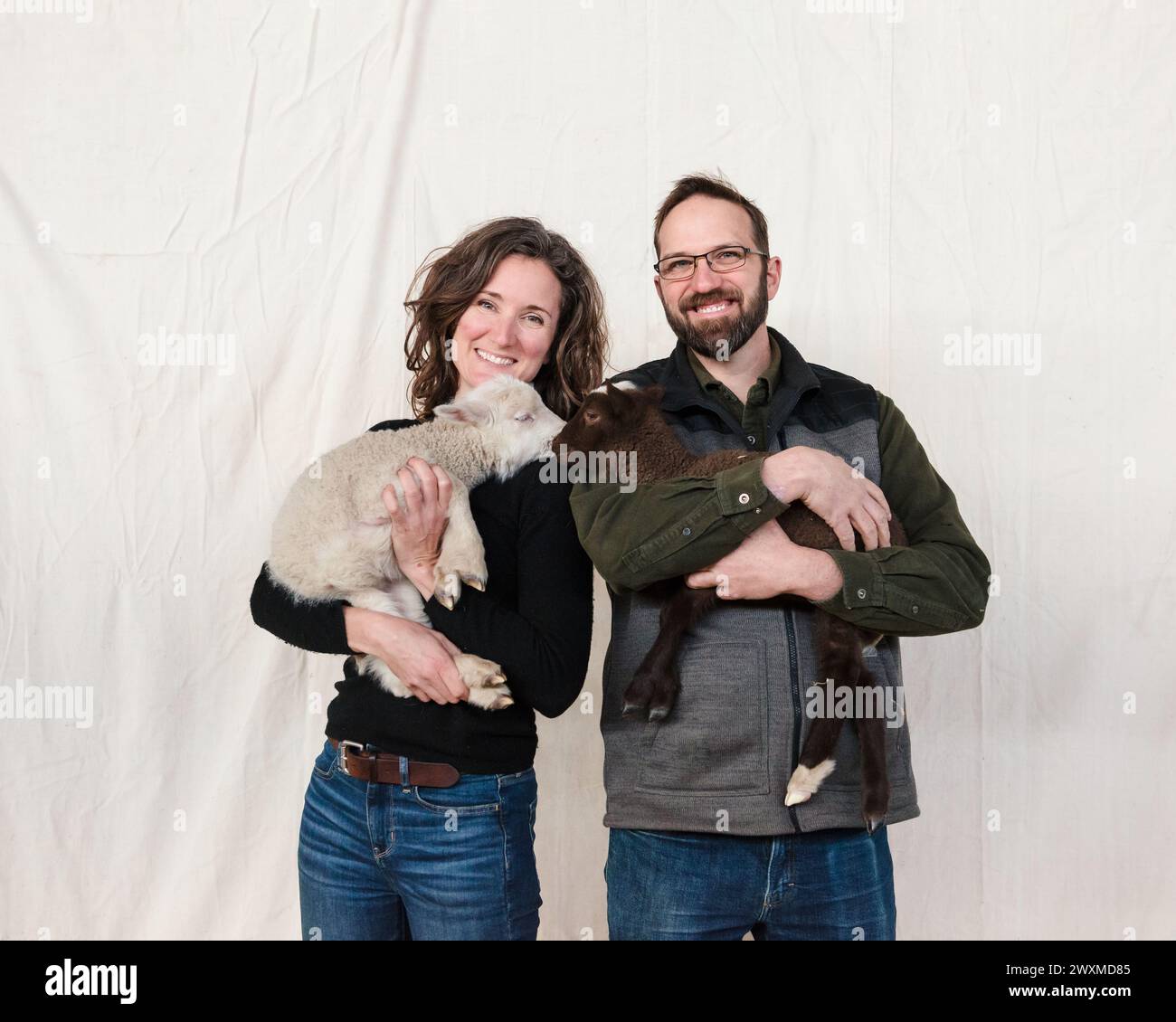 Farm husband and wife posing with lambs Stock Photo - Alamy