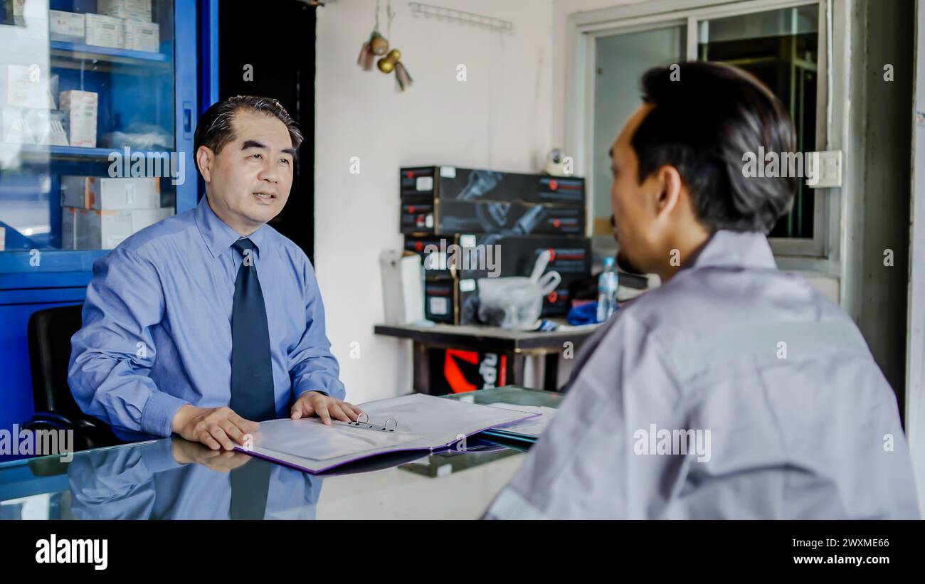 A mechanic discussing car repairment with another person in a garage ...