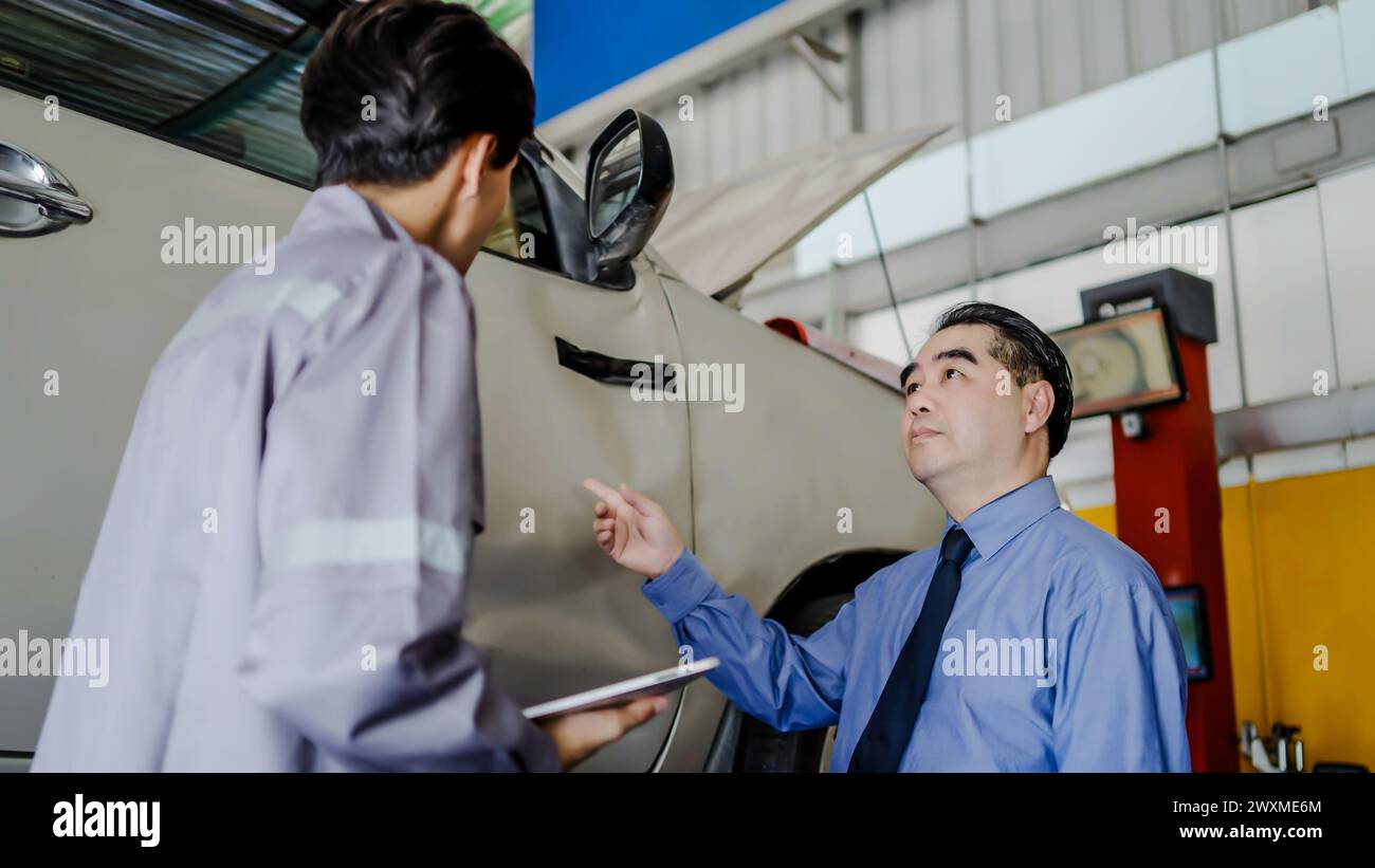 A mechanic discussing car repairment with another person in a garage ...