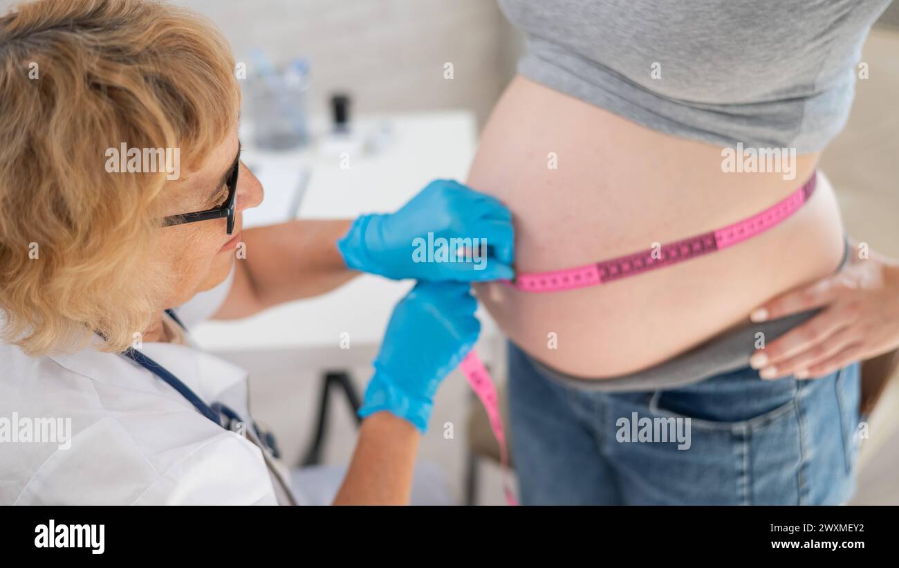 Doctor measuring the volume of a pregnant woman's abdomen using a ...