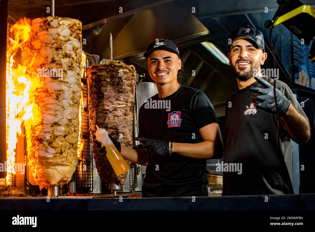 Two men smiling cooking chicken and lamb on rotisseries for kebabs at ...