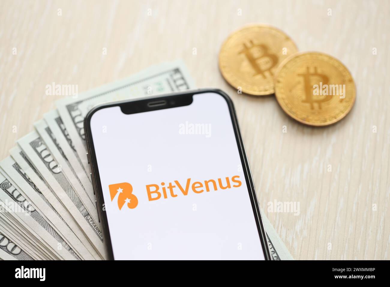 KYIV, UKRAINE - MARCH 15, 2024 Bitvenus logo on iPhone display screen with dollars and bitcoins ...