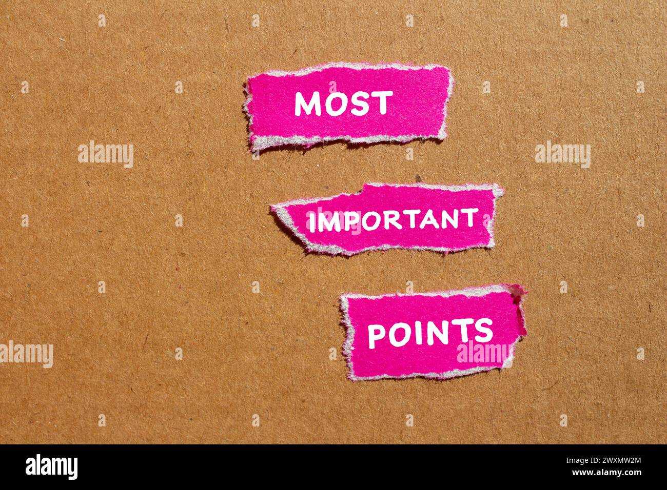 Most important points words written on pink torn paper pieces with ...