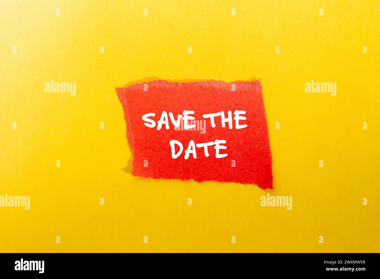 Save the date words written on red torn paper piece with yellow ...