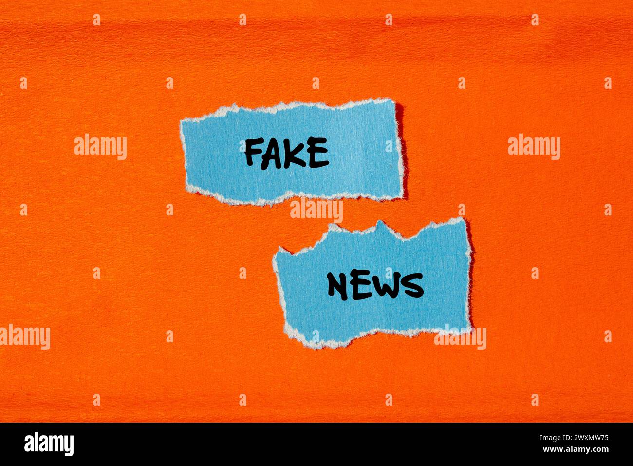 Fake news words written on blue torn paper pieces with orange ...