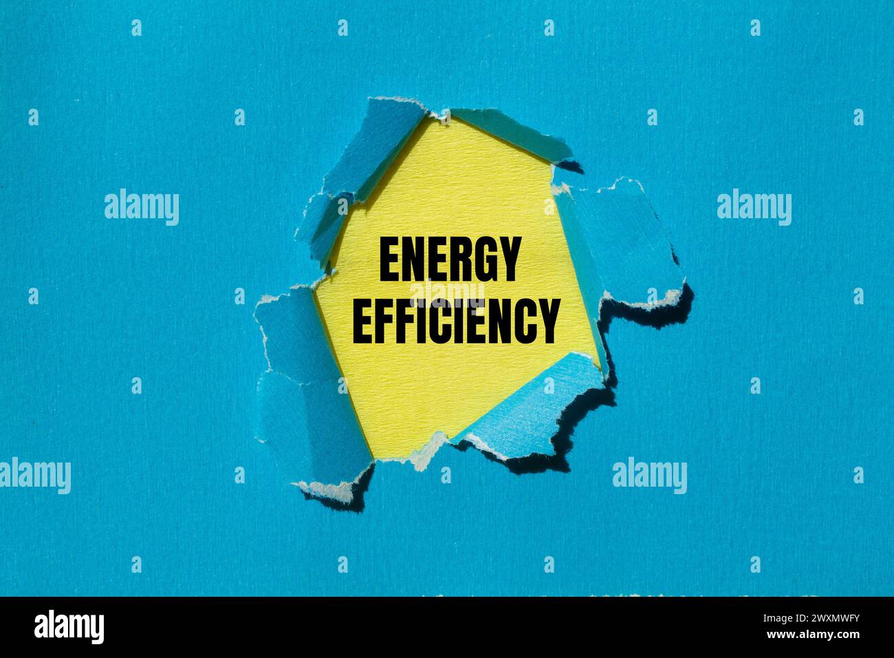 Energy efficiency words written on blue torn paper piece with yellow ...