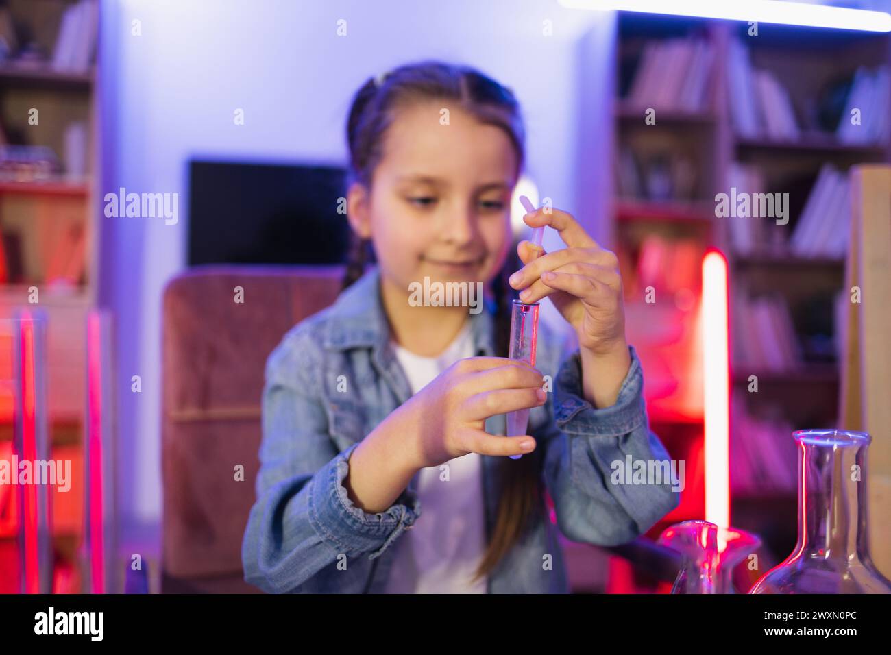 Focused Caucasian little girl doing chemistry experiment looking at ...