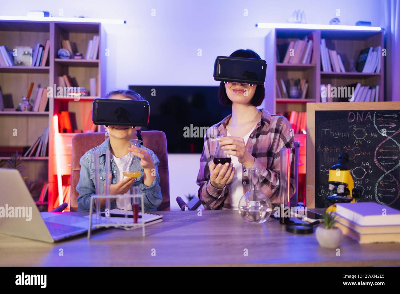 Caring woman and small kid girl improving knowledge using vr glasses at evening home. Caucasian ...