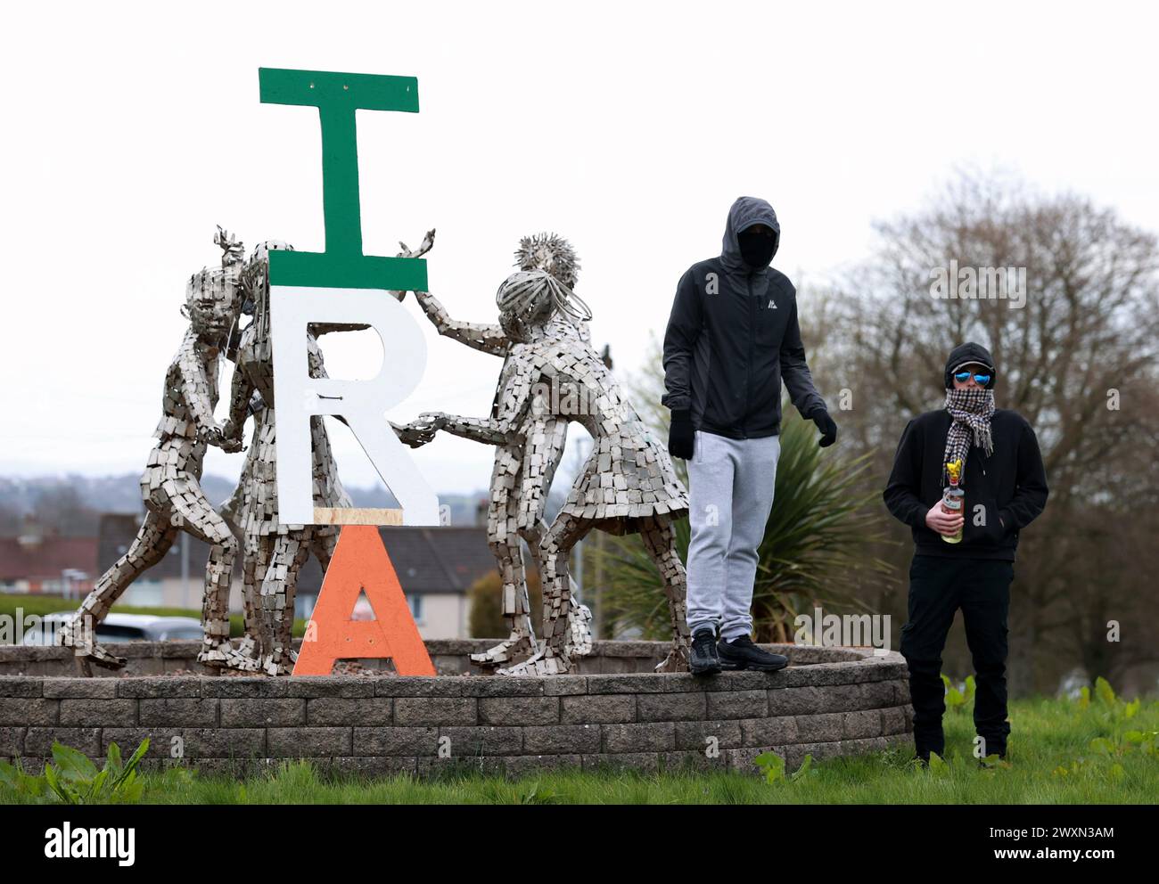 Two young men, one carrying a petrol bomb, stand next to an IRA sign in ...