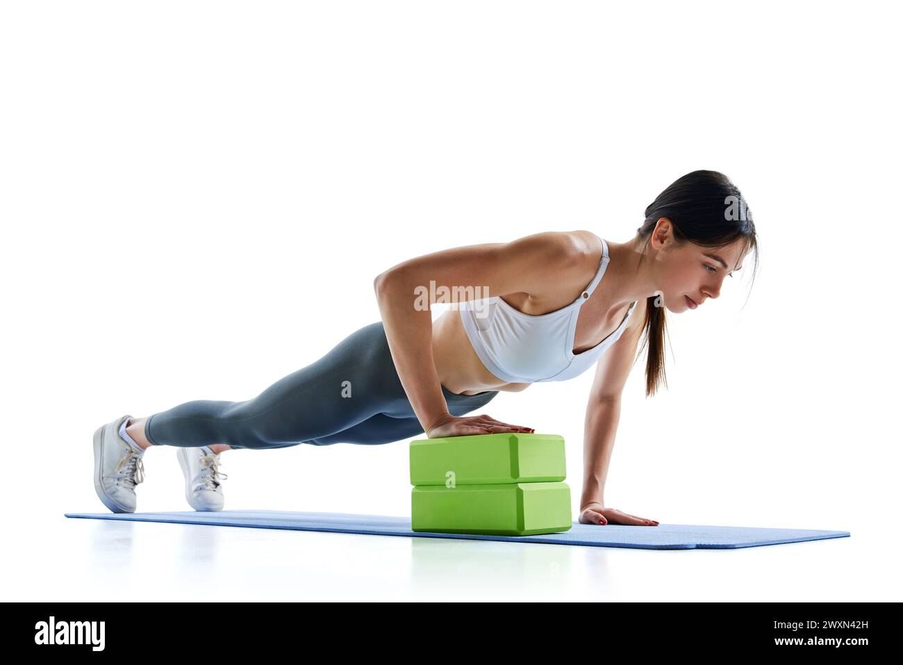 Young, fit, strong woman in legging and top doing push-ups with blocks ...