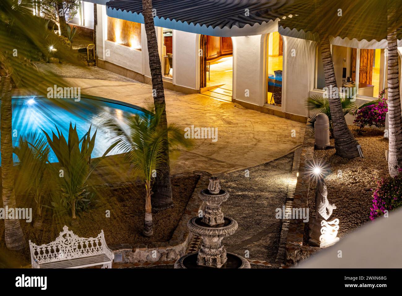 Night view of outdoor rest area in resort with swimming pool, palm ...