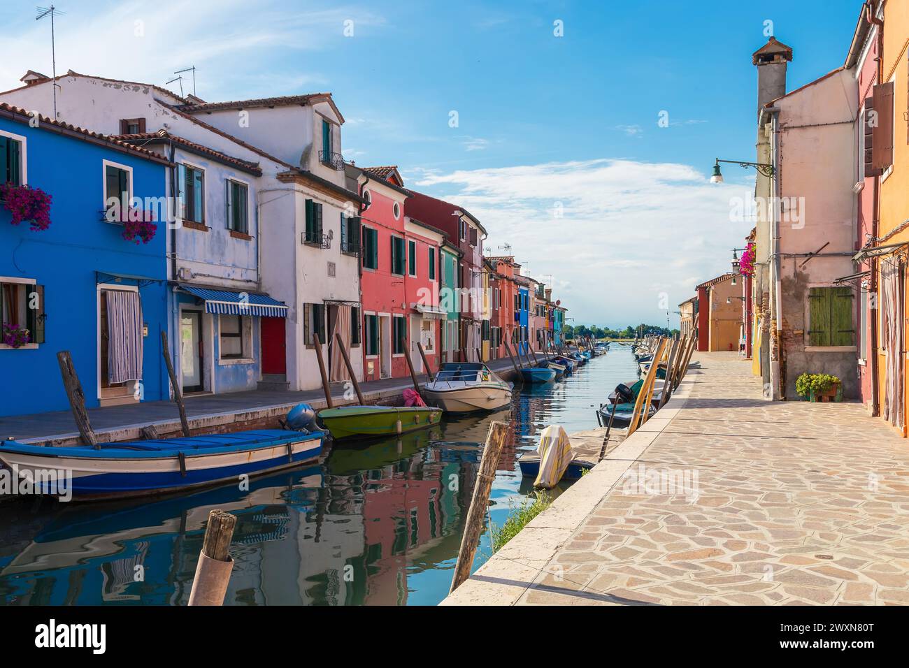 Multicolored colorful houses in Venice on the island of Burano. Narrow canal with motor boats ...
