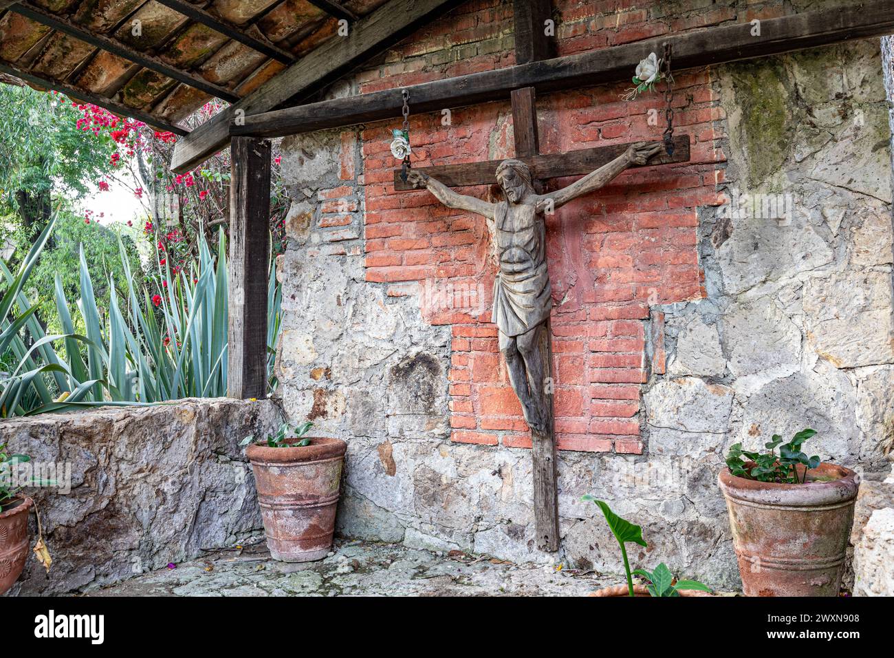 Huge old wooden cross with crucified Christ in shed of ranch, tile roof ...