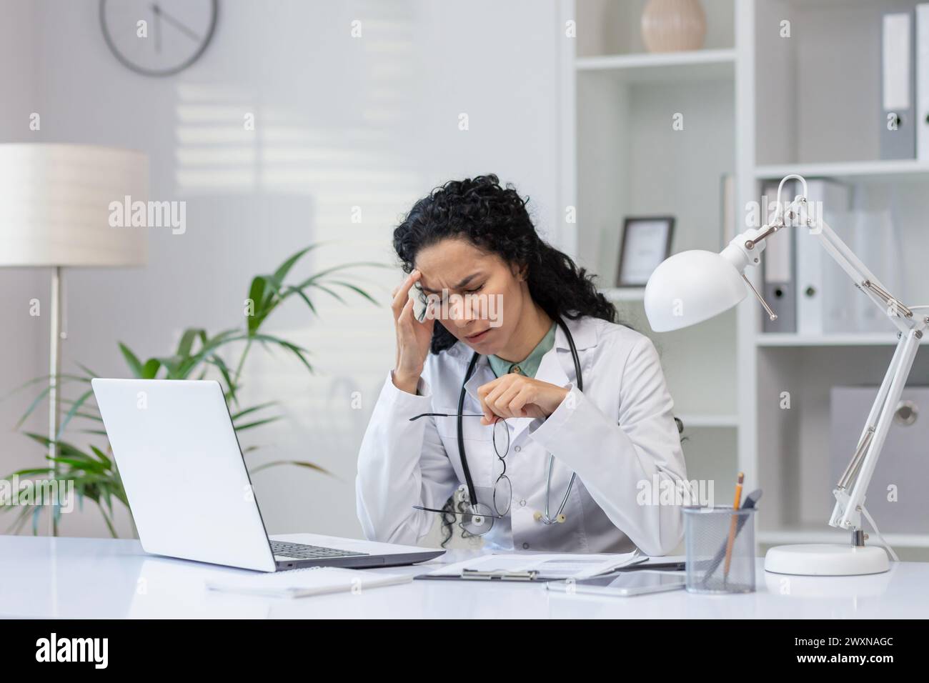 A worried Hispanic female doctor appears stressed while talking on the ...