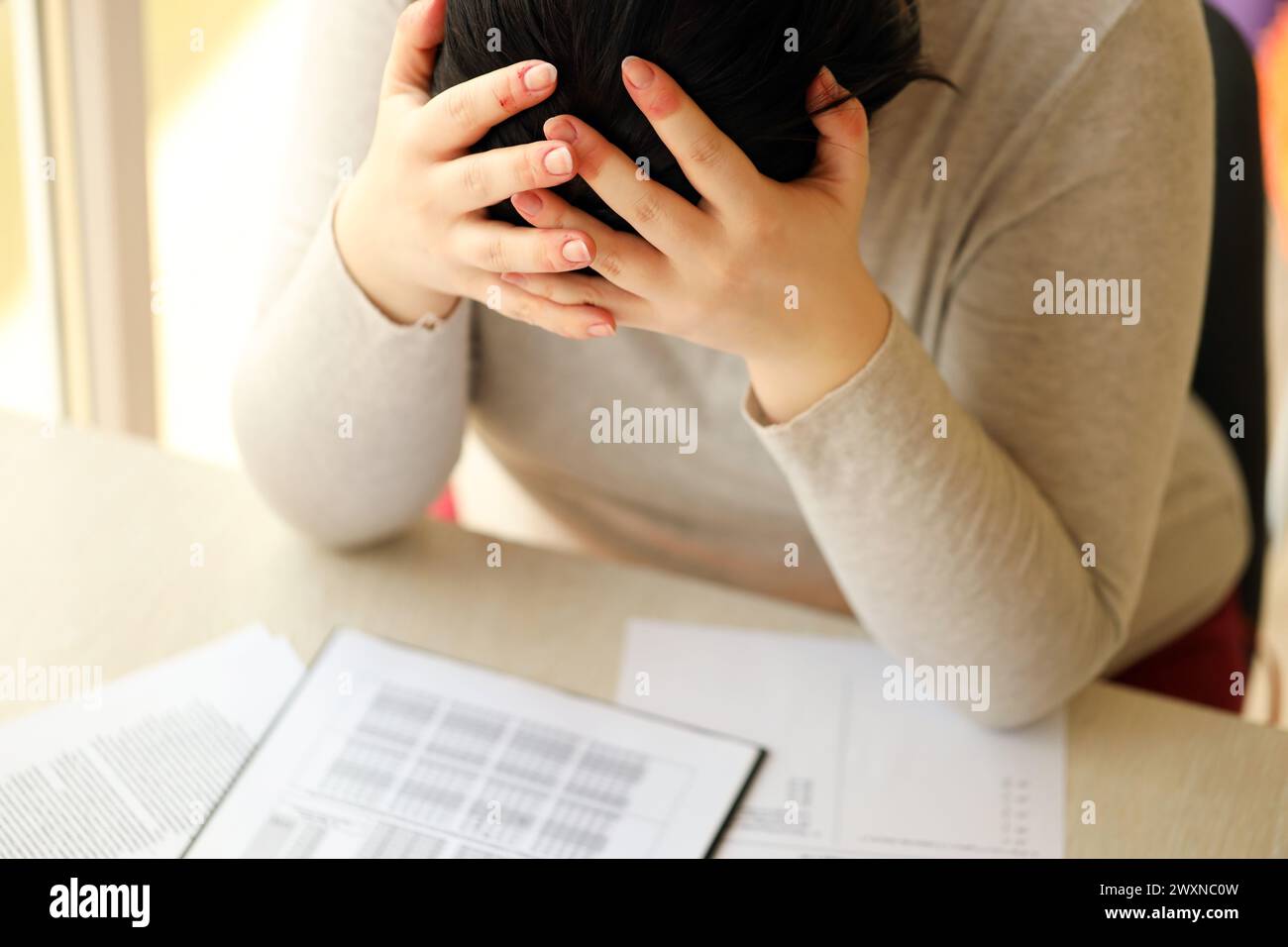 Sad female student testing in exercise and fill exam paper sheet with ...