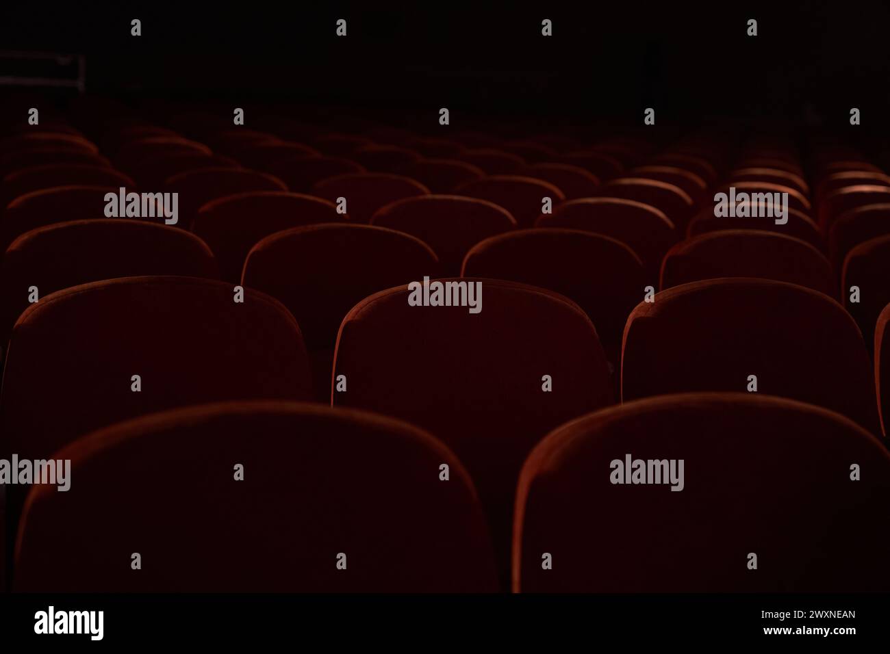 Close up of orange, red seats in dark empty cinema hall with copy space ...