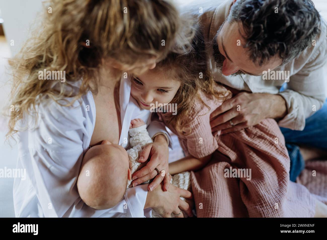 Mother breastfeeding newborn, big sister looking at new baby in mom's ...