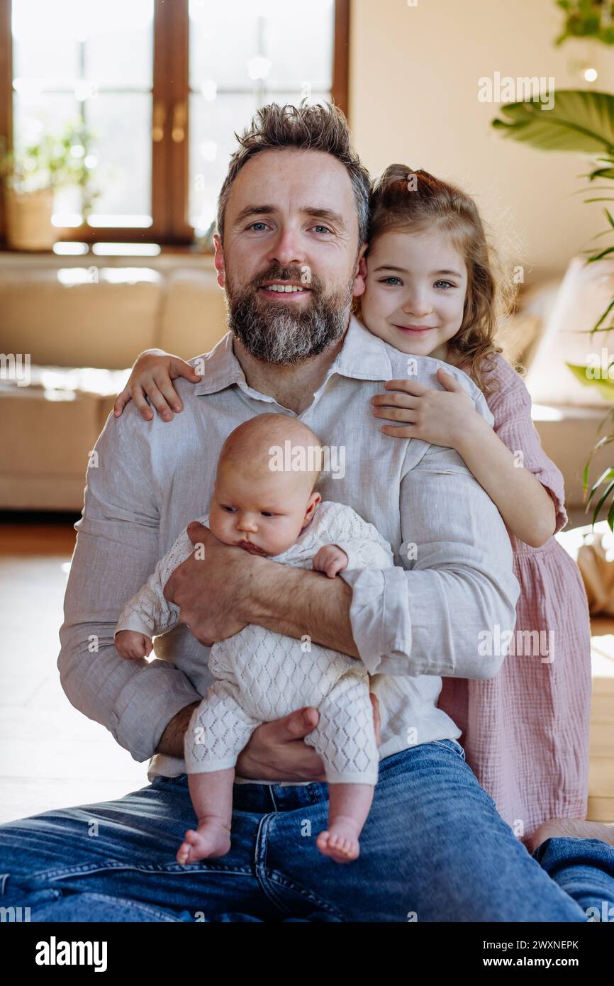 Father holding newborn baby girl, older daughter with them. New sibling ...