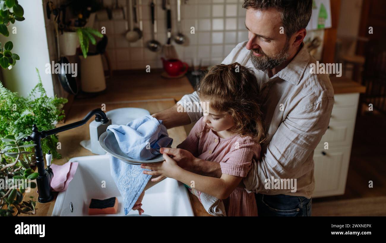 Dad and daughter drying dishes with towels together. Girls dad ...