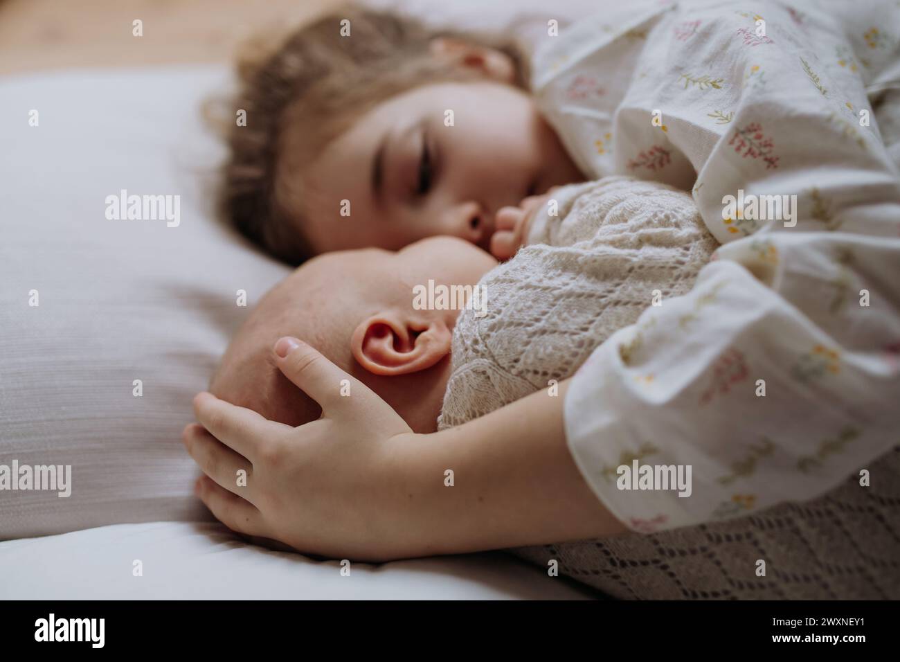 Portrait of big sister cuddling newborn, little baby. Girl lying with ...