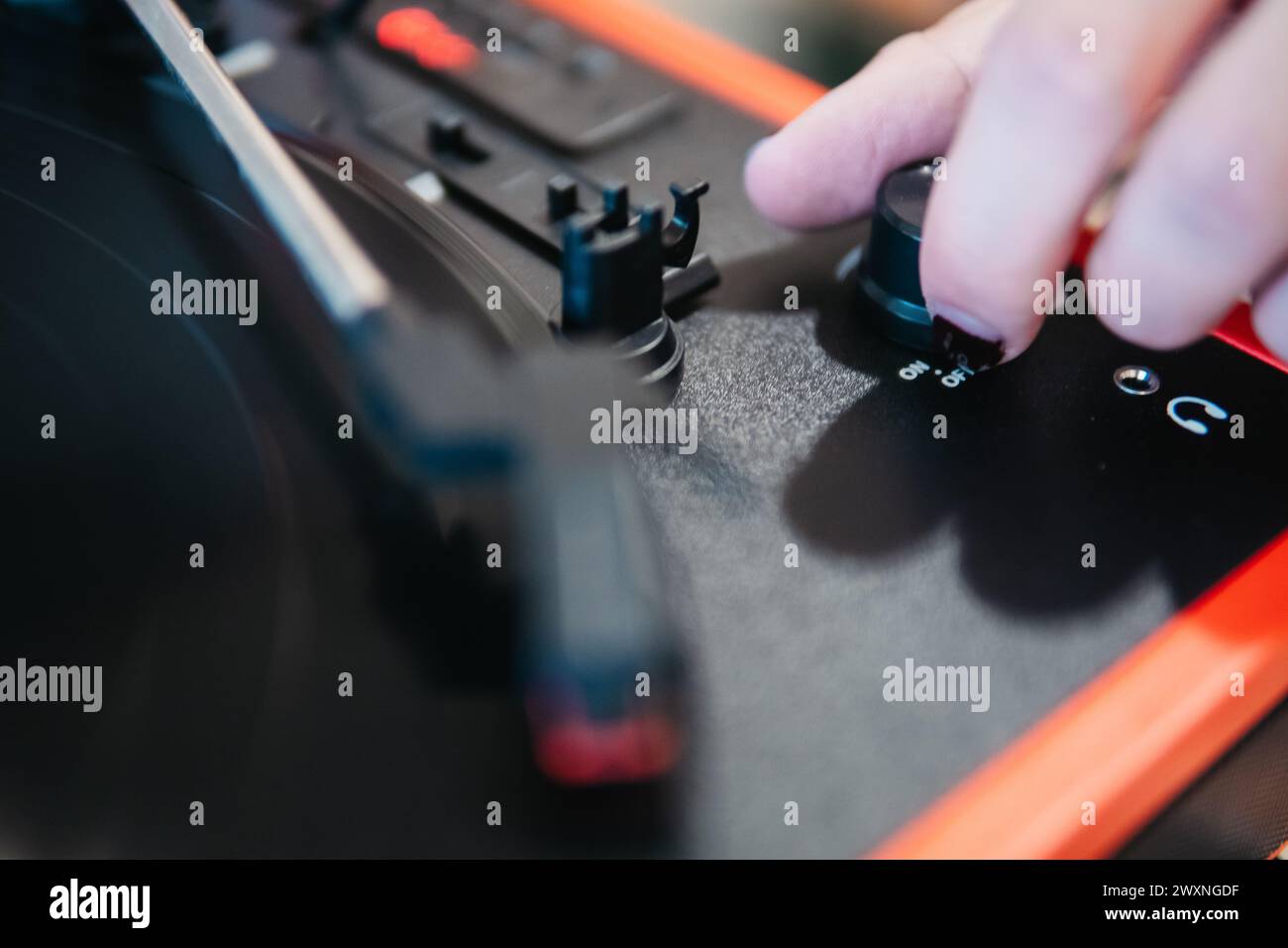 Close-up of a finger adjusting the volume knob on a red portable vinyl ...