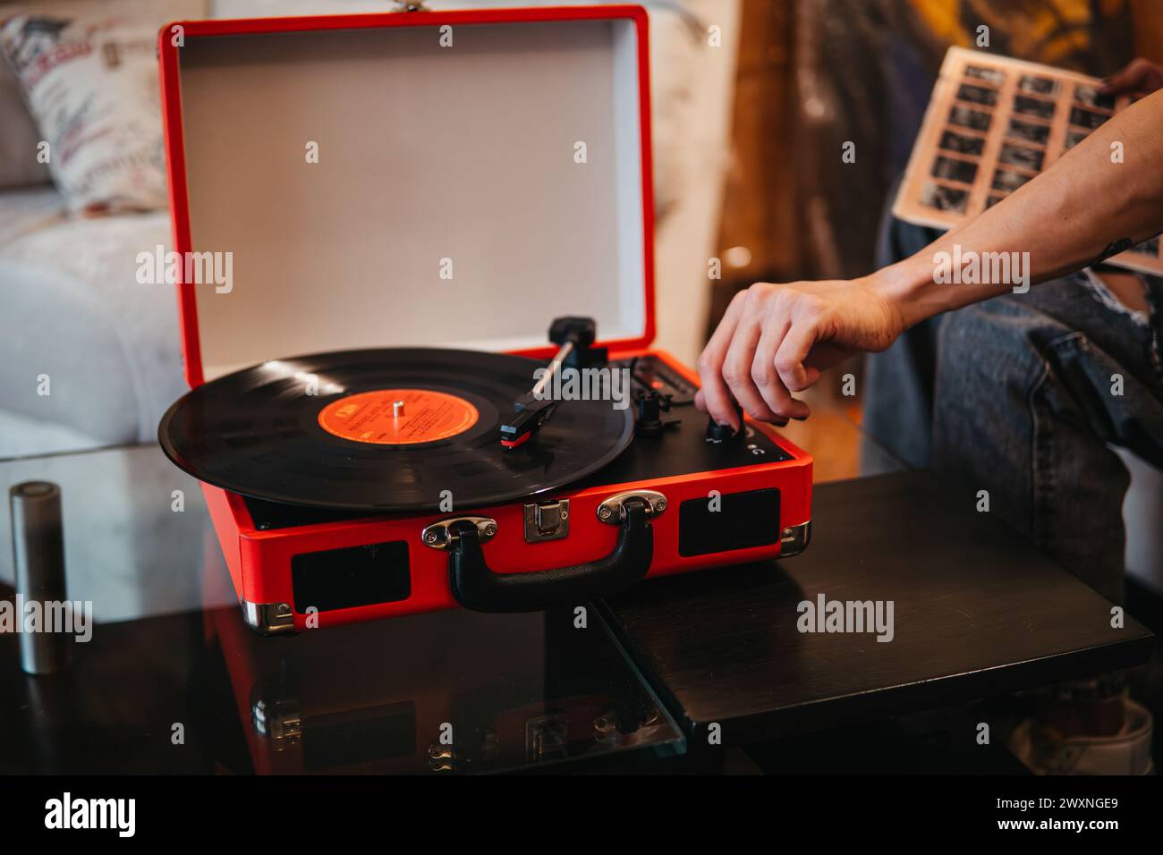 Hand placing a classic black vinyl record onto a red portable turntable ...