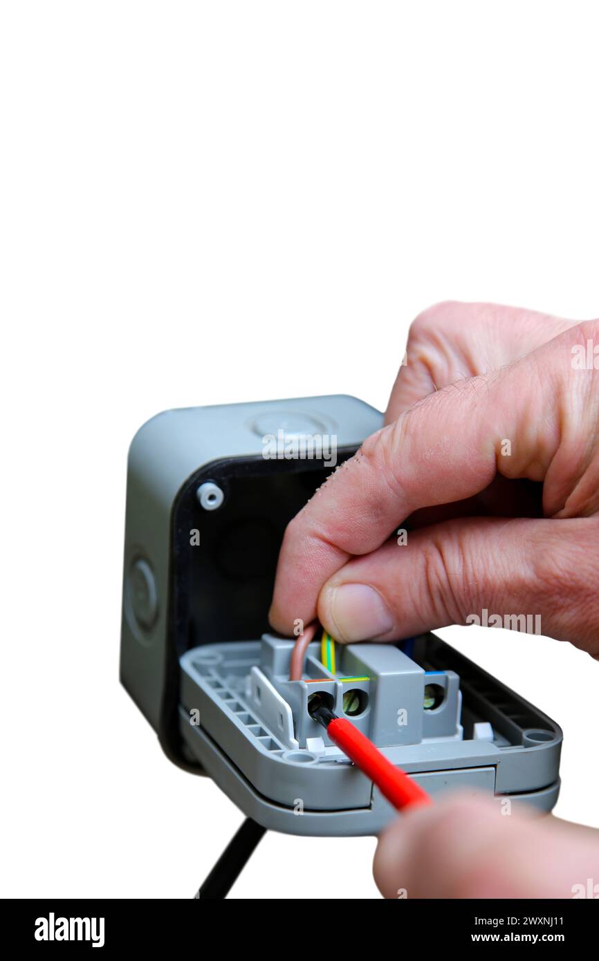 Man wiring an outdoor electric socket using an electrical screwdriver ...