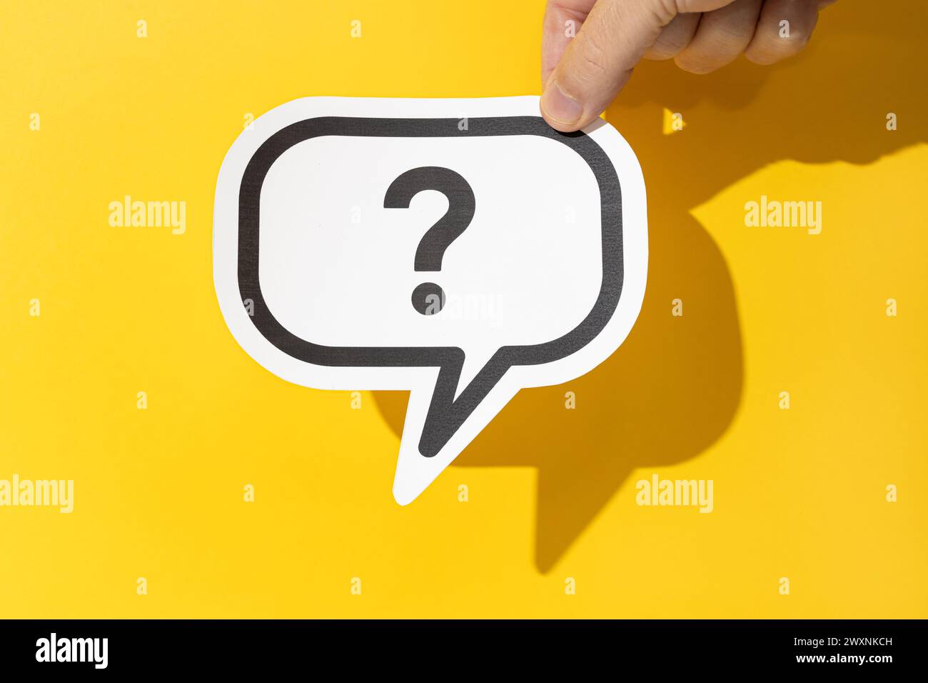 Hand holding a question mark on speech bubble on yellow background ...