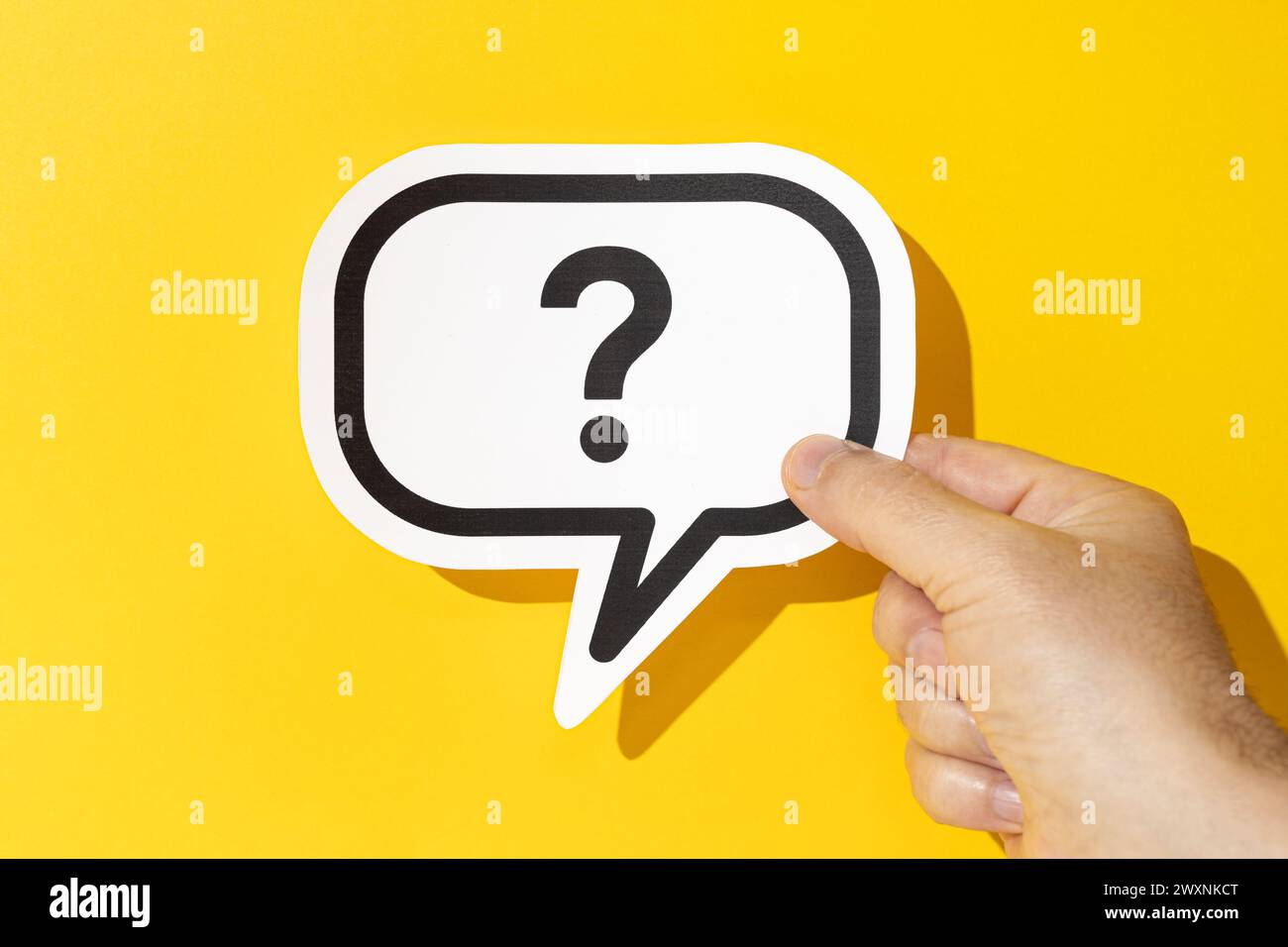 Hand holding a question mark on speech bubble on yellow background ...