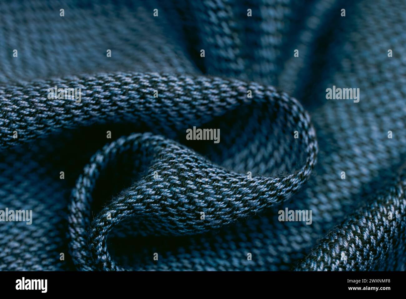 A close-up of blue knitted fabric with a loop knot, highlighting thread ...