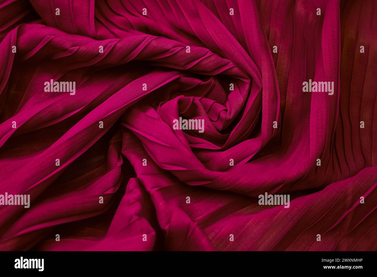 A pink silk fabric folded with a striped design in orange and brown ...