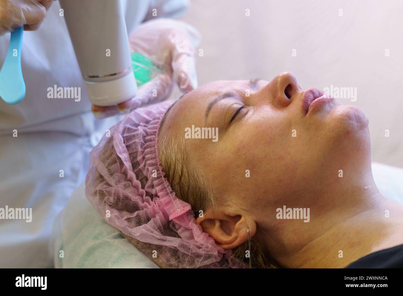 A woman having a facial mask applied to her face in a spa setting for ...