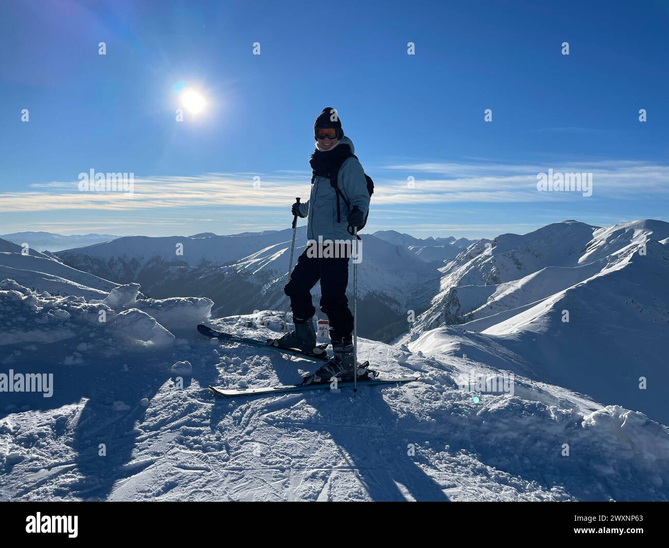 Skier standing on snowy mountain peak with skis Stock Photo - Alamy