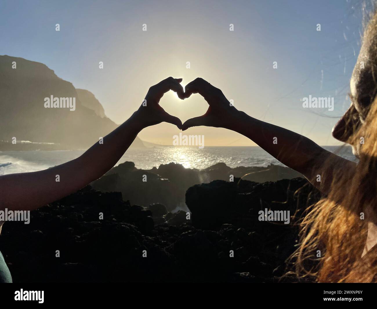 Two women forming a heart shape with hands at sunrise Stock Photo - Alamy
