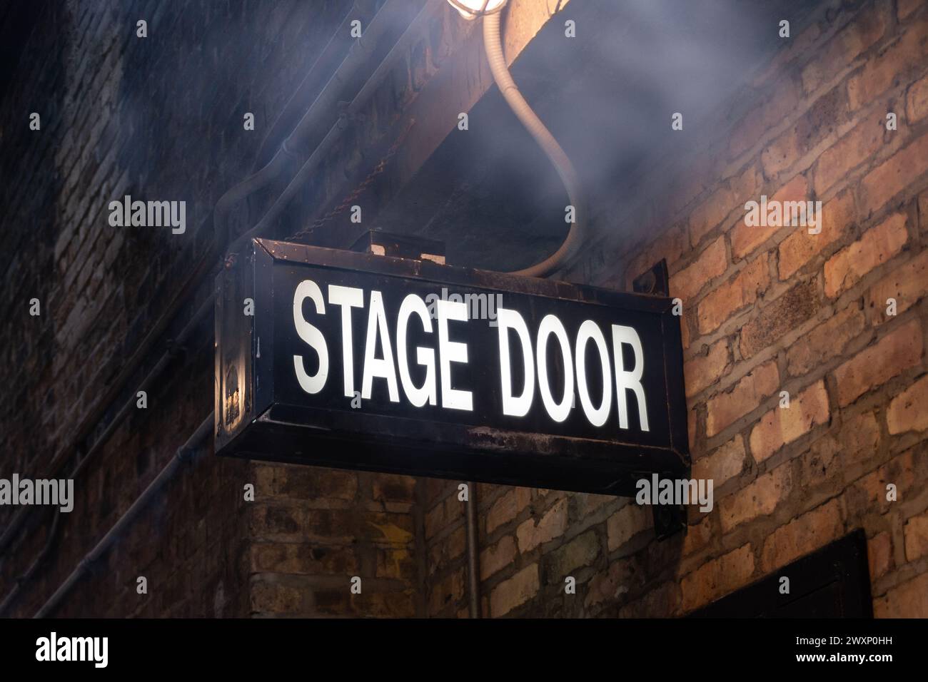 Vintage illuminated stage door sign in a dark and dingy back alley in ...