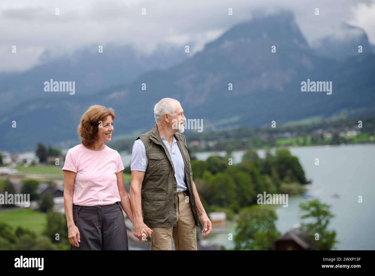 Active elderly couple hiking together in spring mountains. Senior tourists enjoying nature and ...